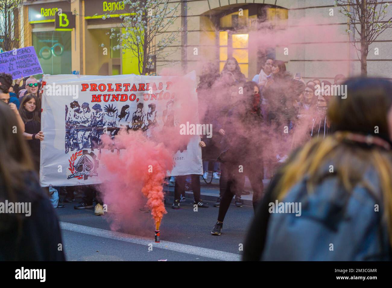 A Crowd marching with signs in middle of orange smoke flare during 8M ...
