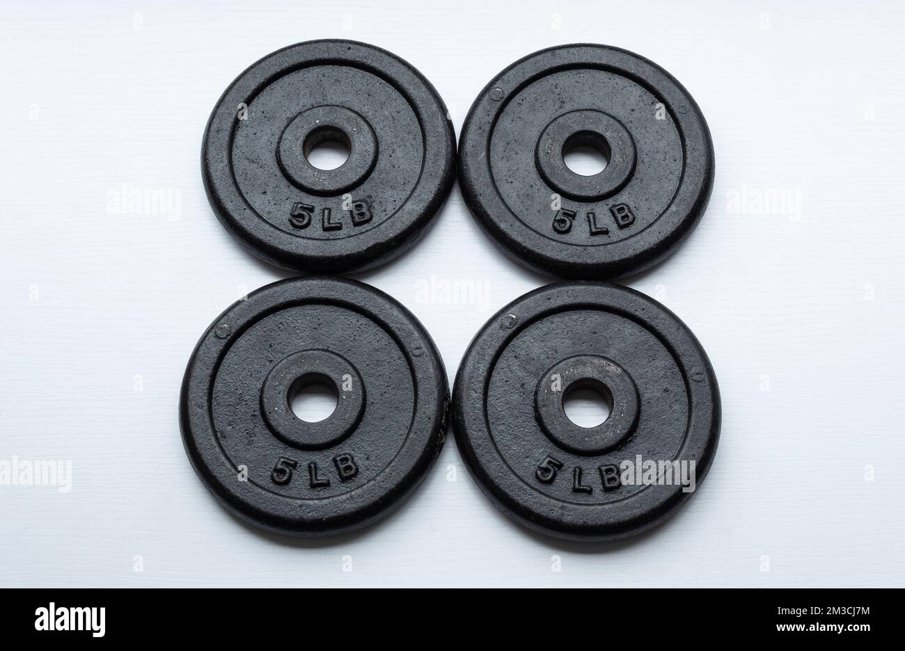 Closeup to a four dumbbell disc of 5 pounds over white background ...