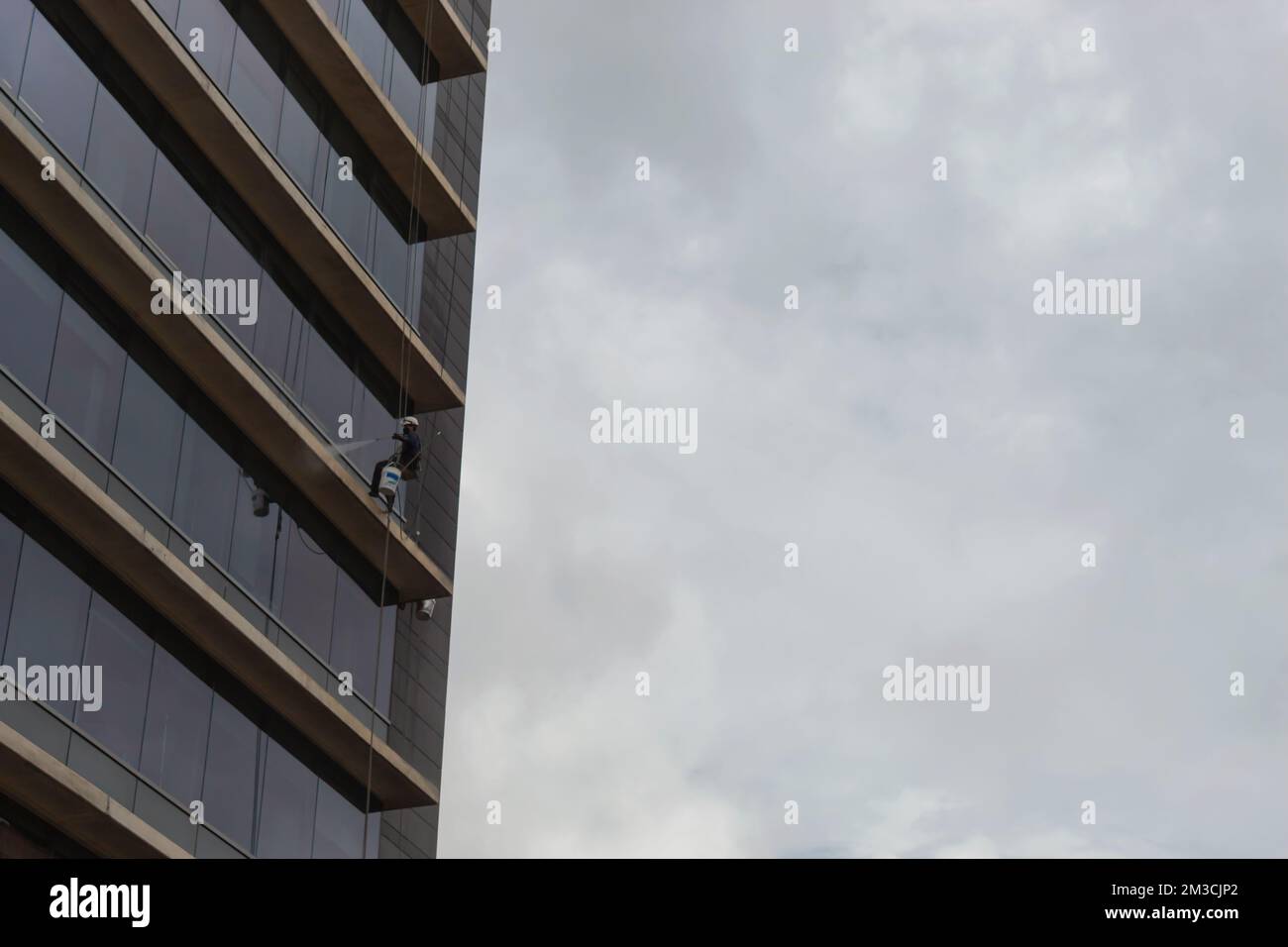 A windows washer doing his job at high modern skyscraper corner with ...