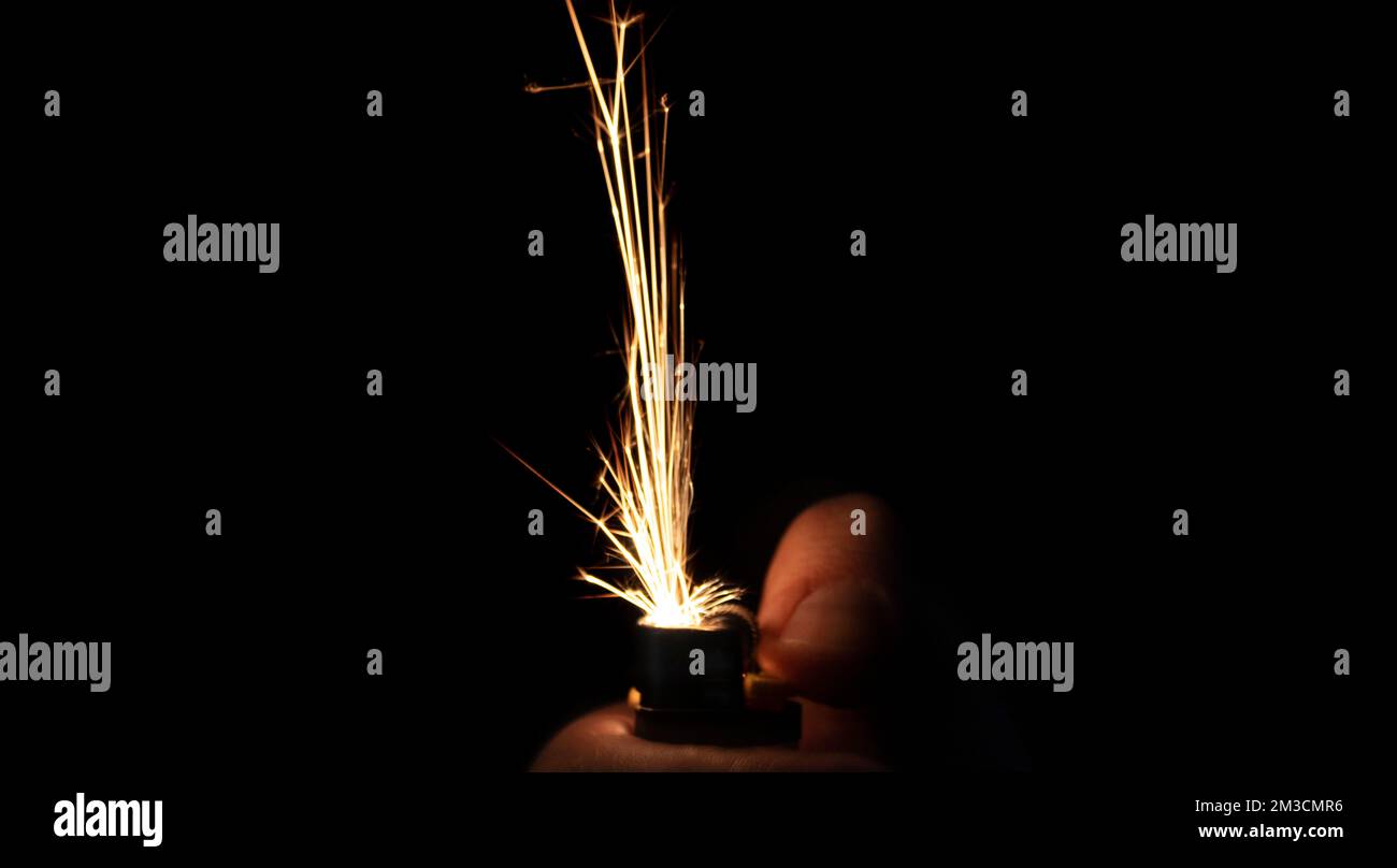 Closeup to hand igniting fire lighters with black background. Energy ...
