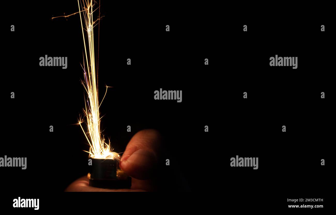 Closeup to hand igniting fire lighters with black background. Energy ...