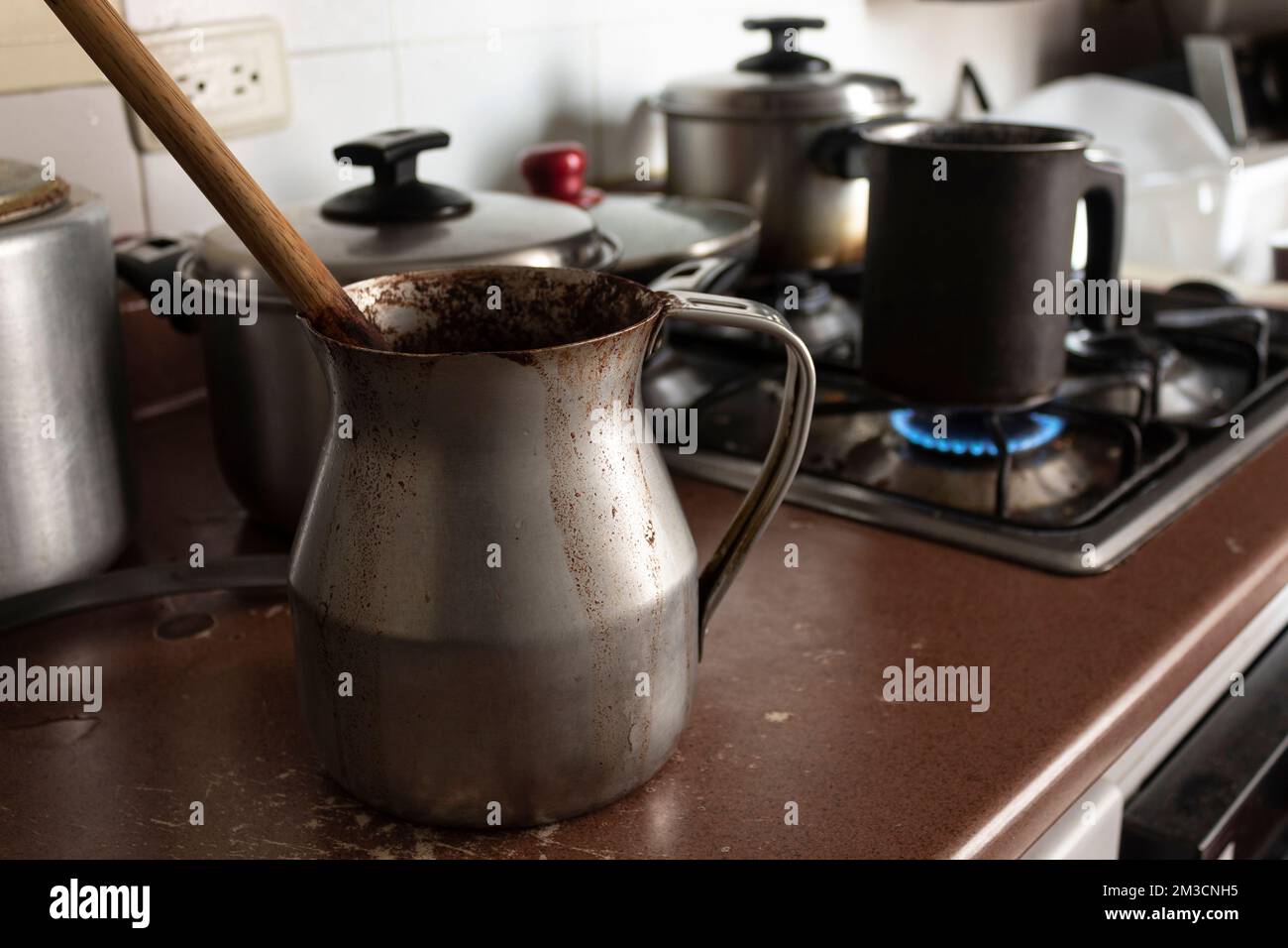Old dirty cocoa cooking pot over kitchen furniture with gas stove on ...