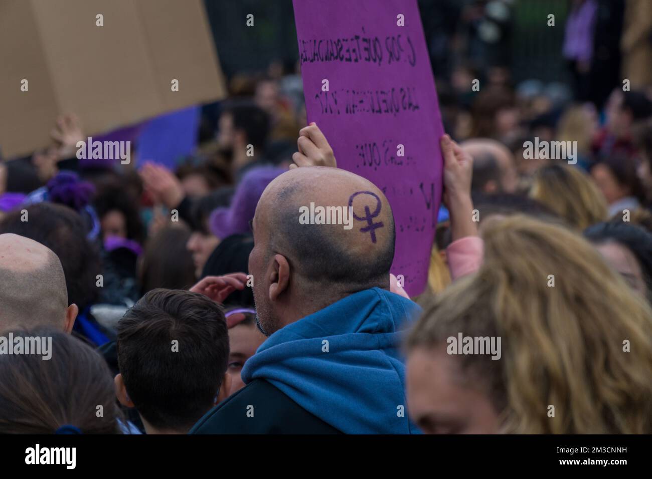 A bald man with violet female symbol painted in his head during 8M ...