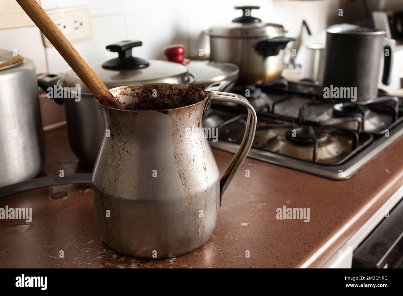 Old dirty cocoa cooking pot over kitchen furniture with gas stove and ...