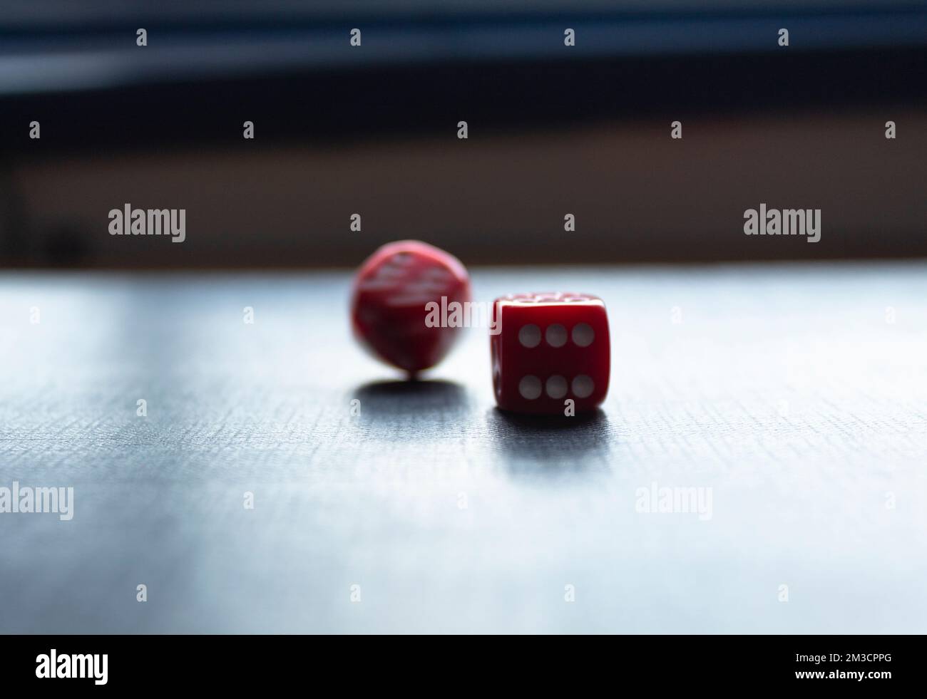 Closeup to a red dices, one dice is spinning over a black background ...