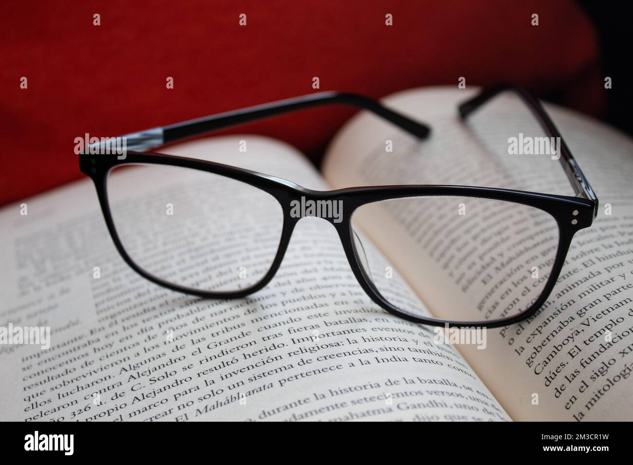 Closeup to a black reading glasses over a spanish text open book with ...