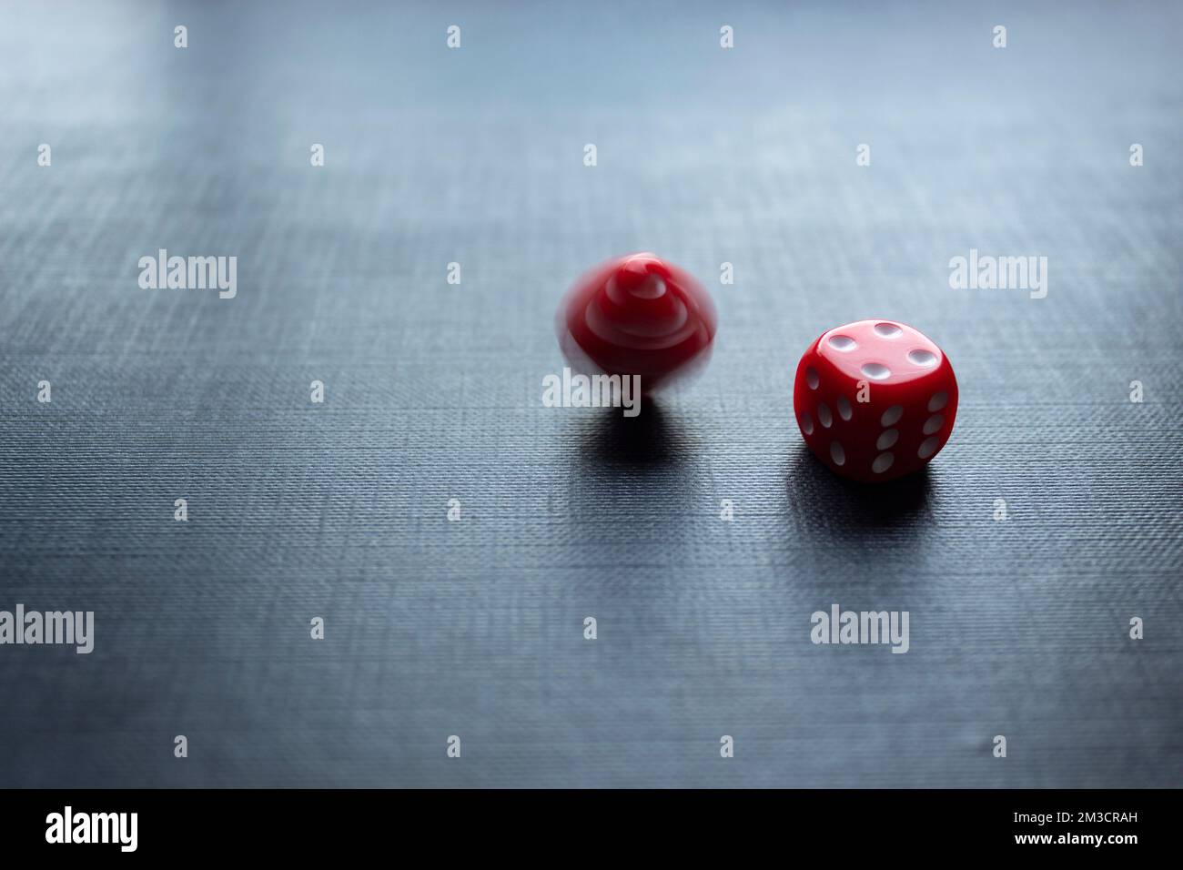 Closeup to a red dices, one dice is spinning over a black background ...