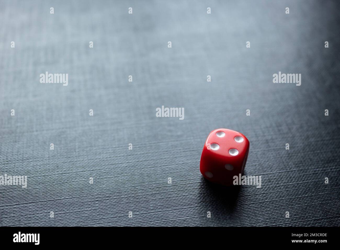 Closeup to a lonely red dice over a black background. Ideal fo gamble ...