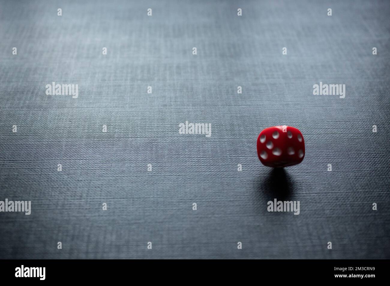 Closeup to a lonely red dice spinning over a black background. Ideal fo ...