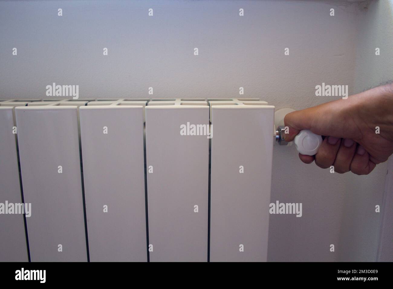 Image of a man's hand closing the knob of a radiator. Problem of the ...