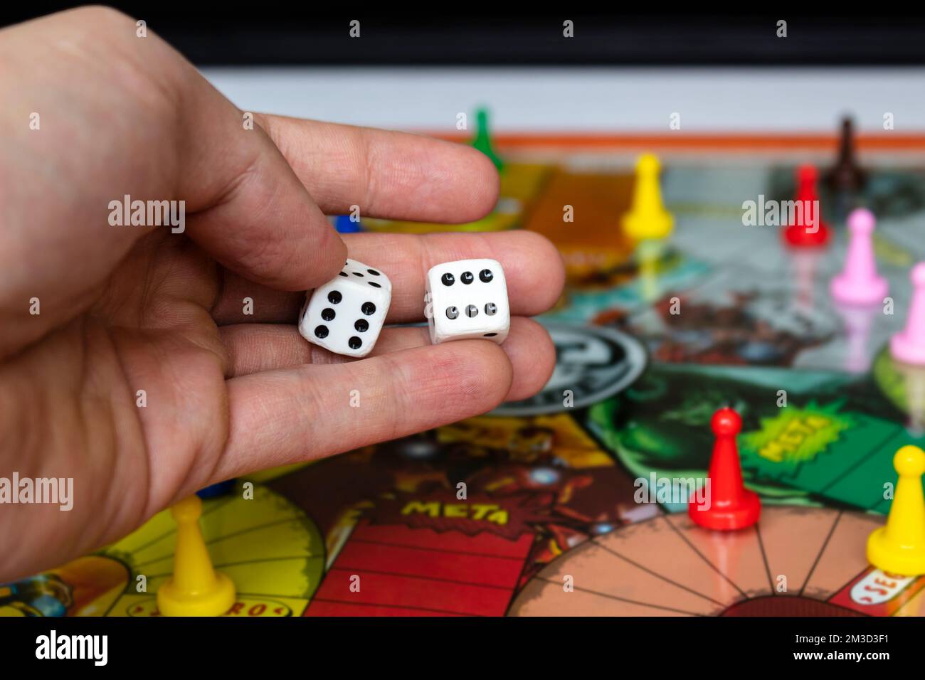 Hand holding a double six old white dices over a board game with color ...