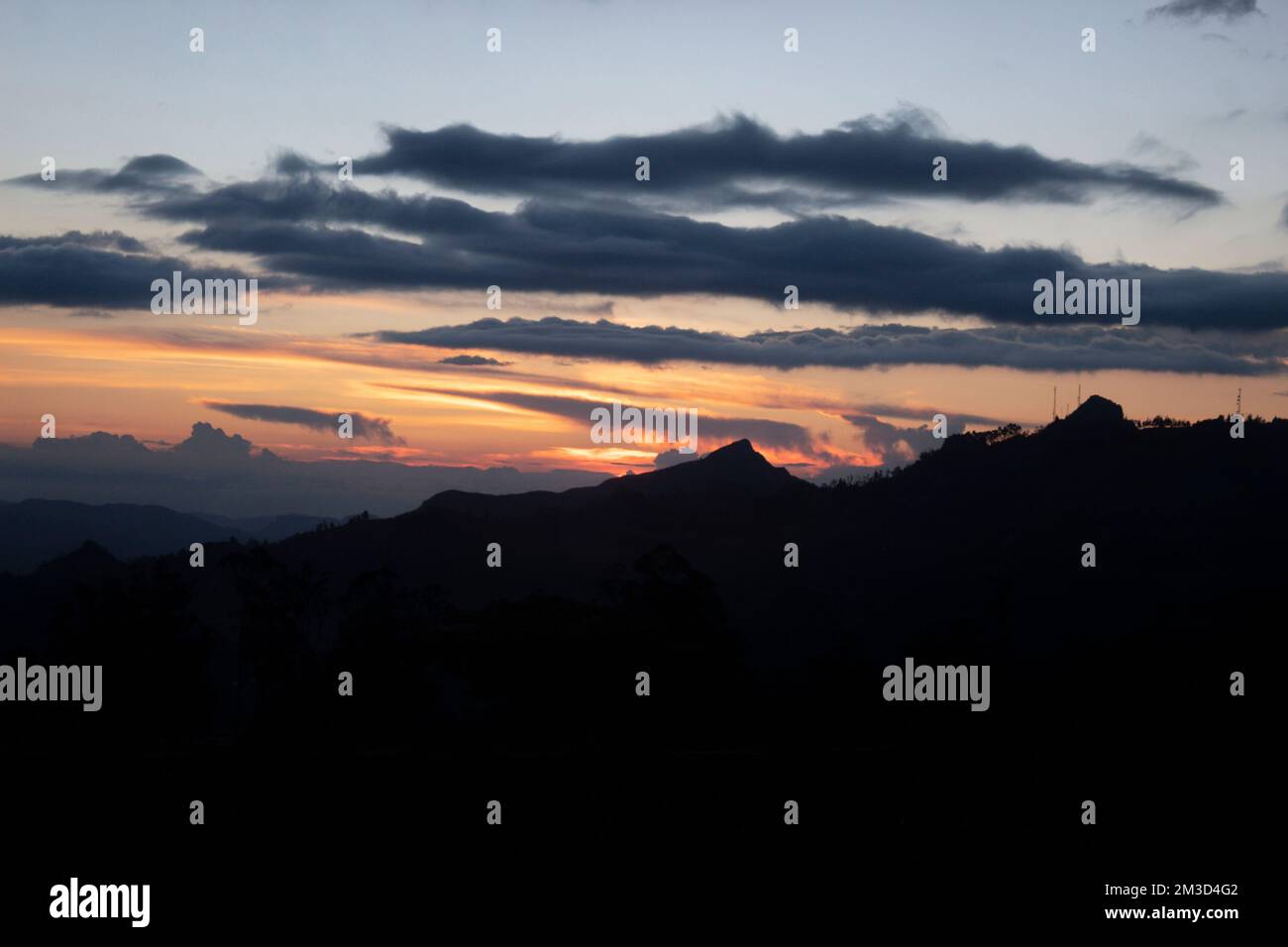 Beautiful orange and blue sunset with a huge mountain rage silhouette ...