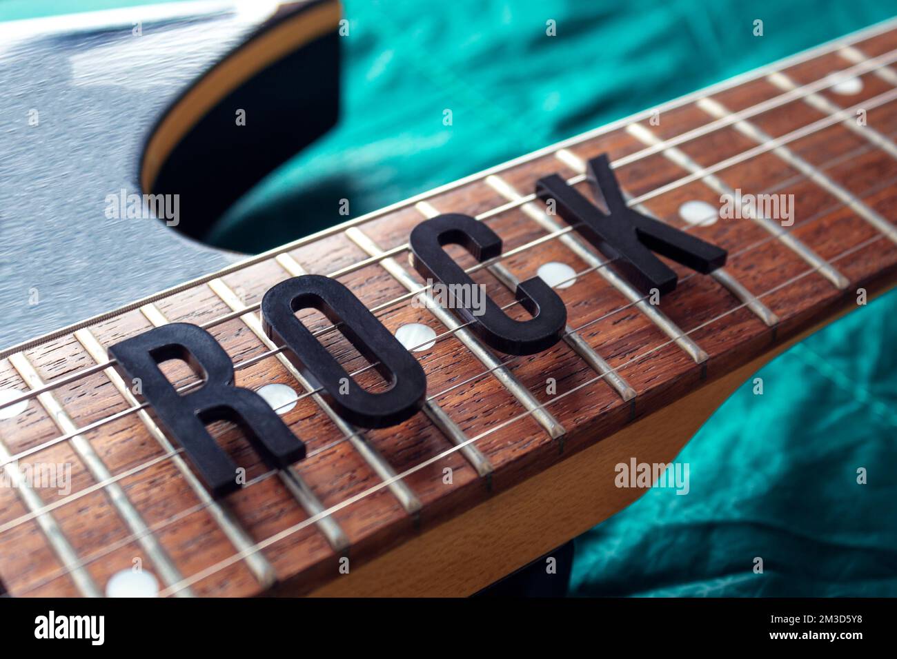 Closeup to a ROCK lettering black word over a six electric guitar ...