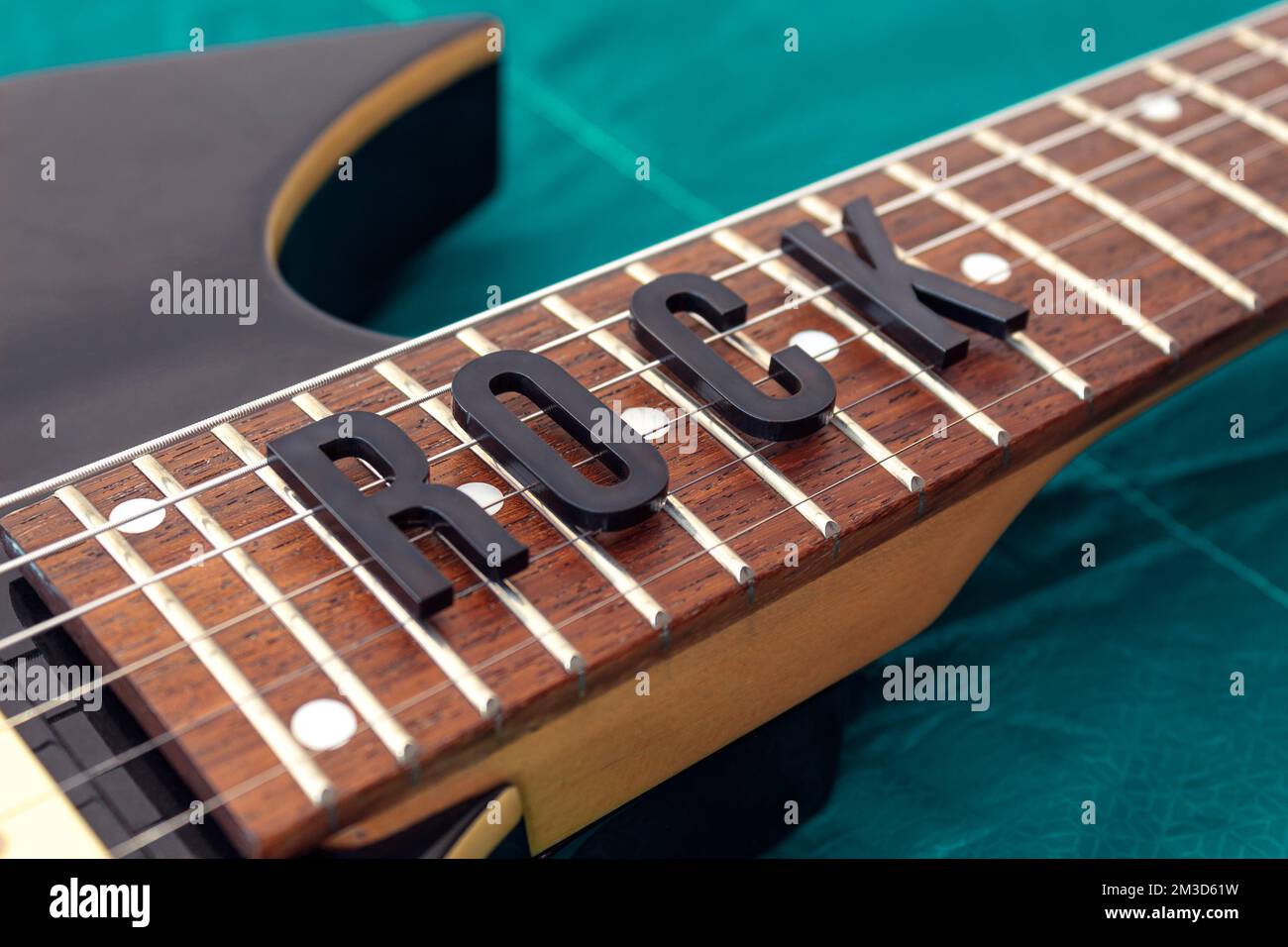 Closeup to a ROCK lettering black word over a six electric guitar ...