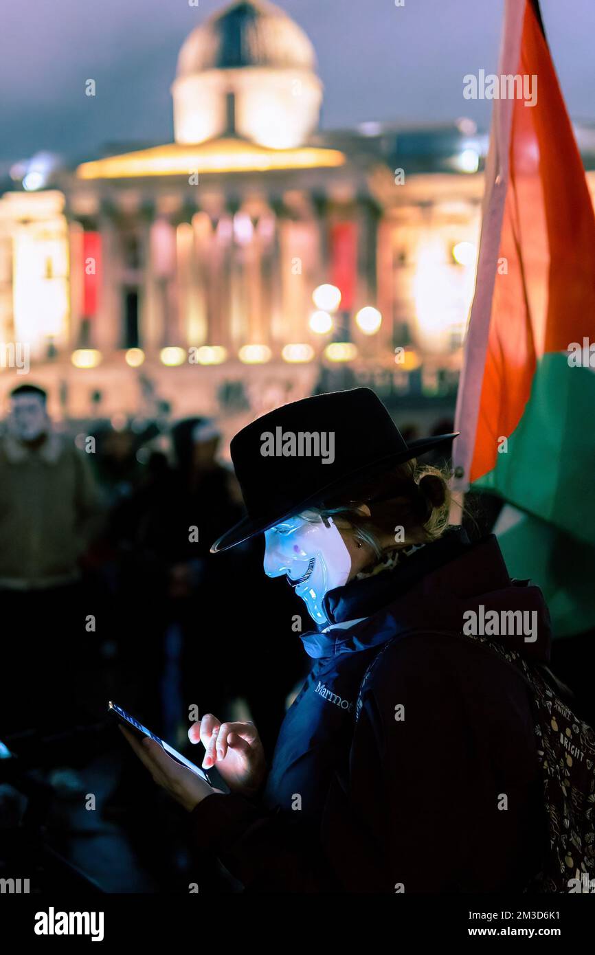 London, UK. 23rd Nov, 2022. A protester wearing a Guy Fawkes mask uses ...