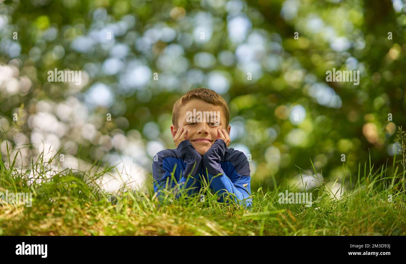 A portrait of a young happy boy in a green park, in deep thought Stock ...