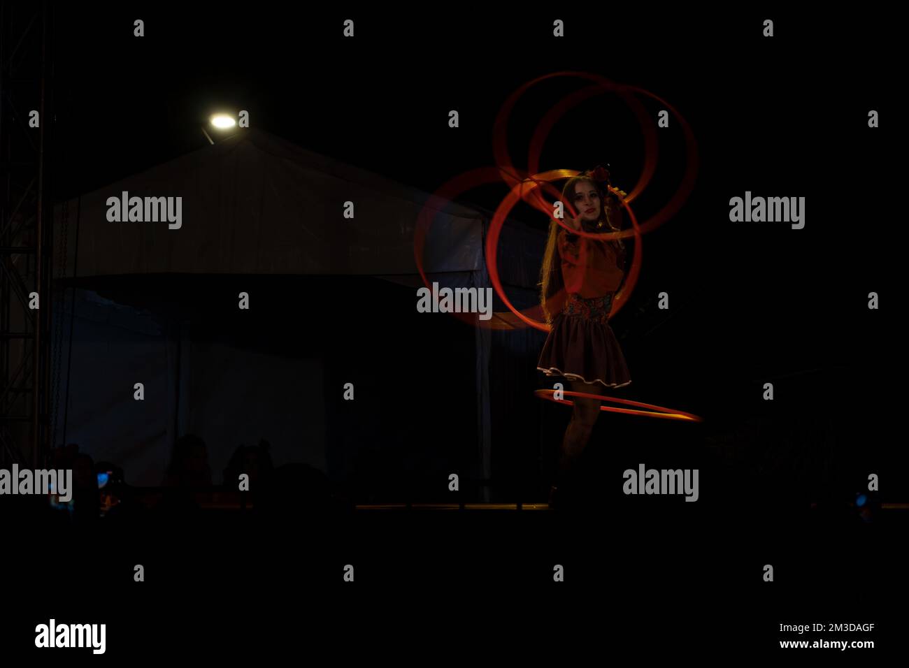 latin woman dancing with a very big hoop, at night with ambient lights ...