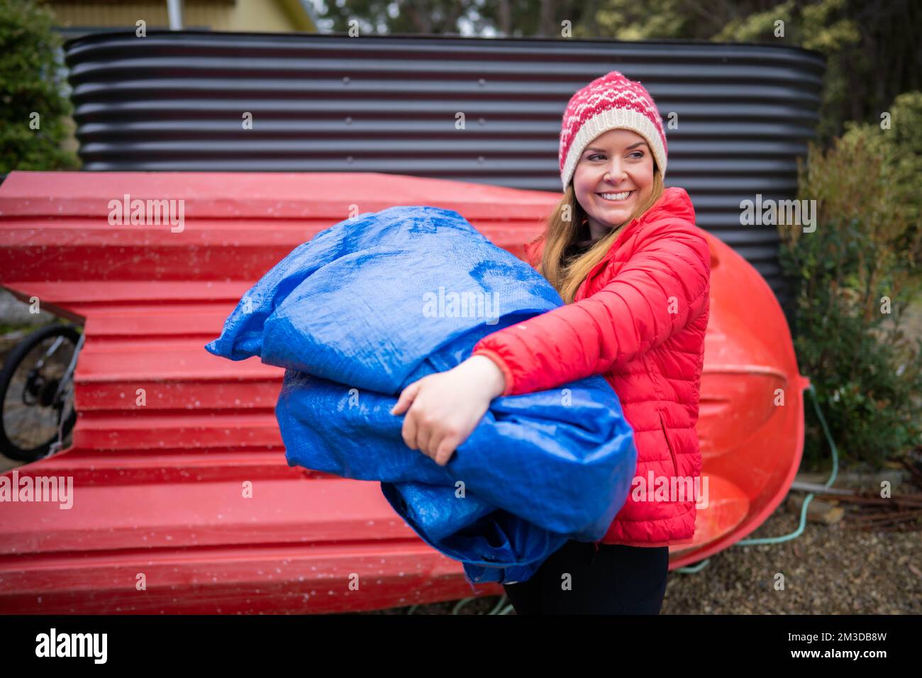 woman folding up a tarp at a campground in australia. camping tant and ...