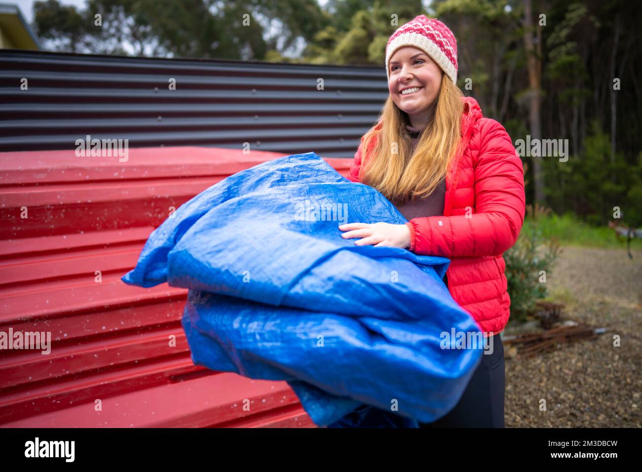woman folding up a tarp at a campground in australia. camping tant and ...