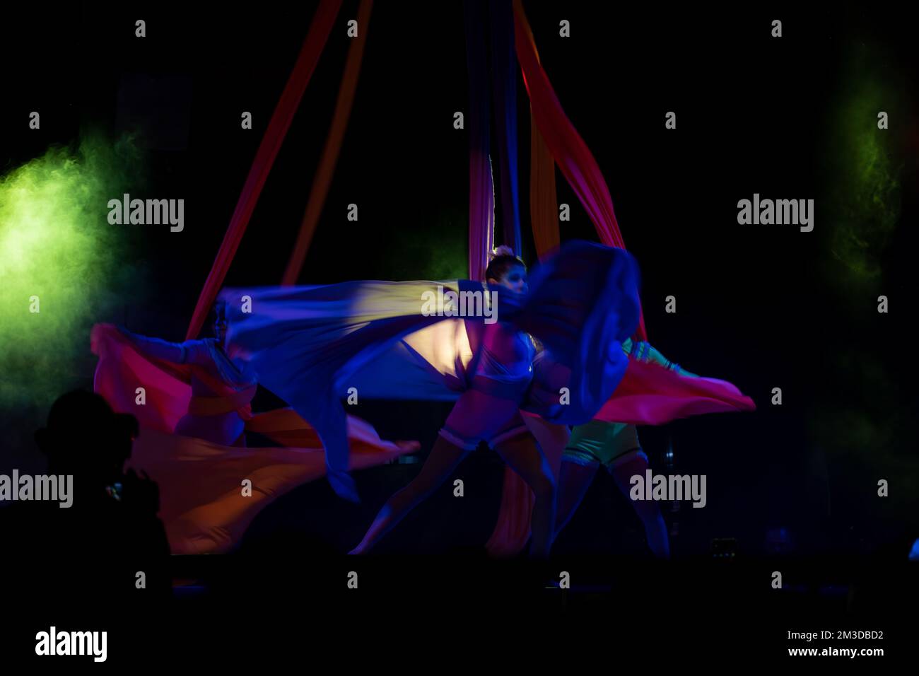 Professional aerialist circus performer on red bright aerial silks ...