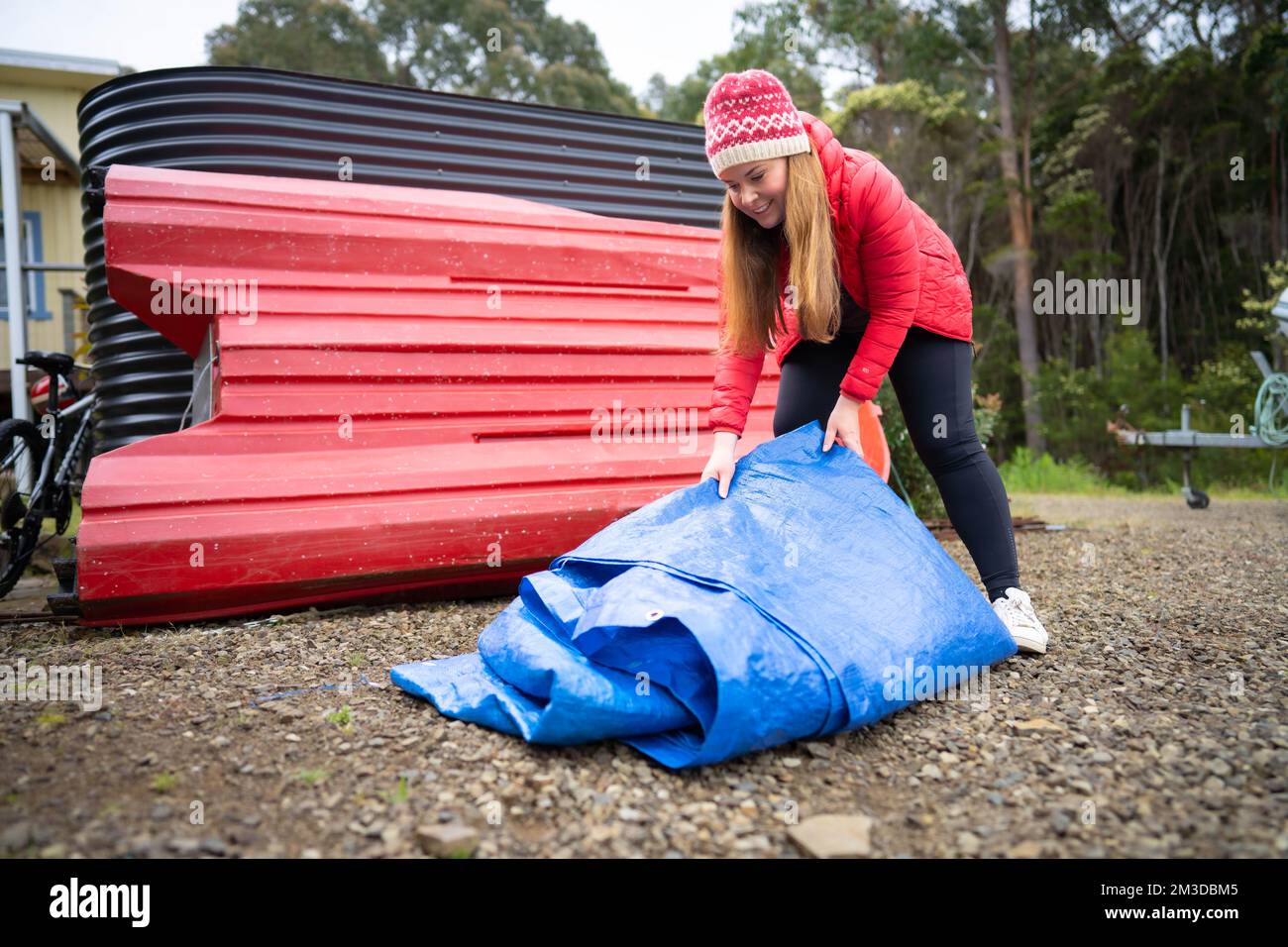 woman folding up a tarp at a campground in australia. camping tant and ...