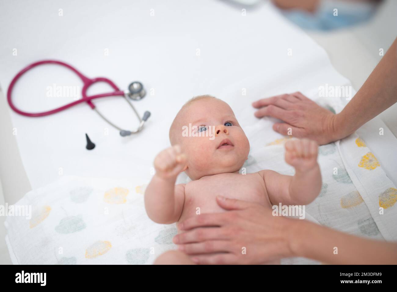 Baby lying on his back as his doctor examines him during a standard ...