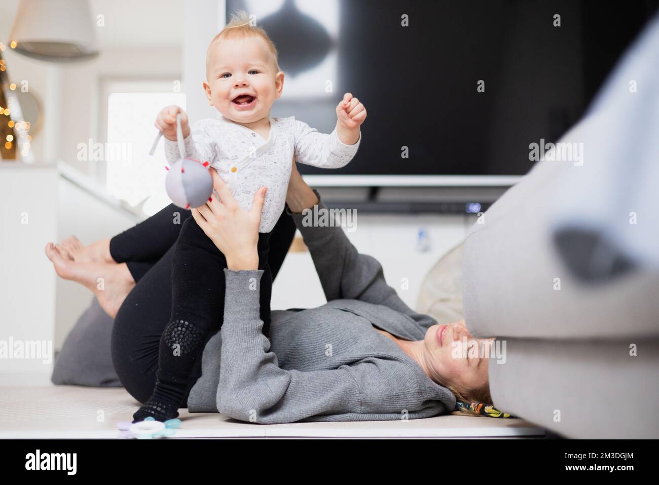Happy family moments. Mother lying comfortably on children's mat ...