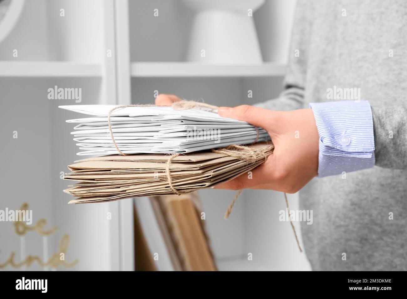 Woman holding tied letters near shelf unit, closeup. Mail concept Stock ...