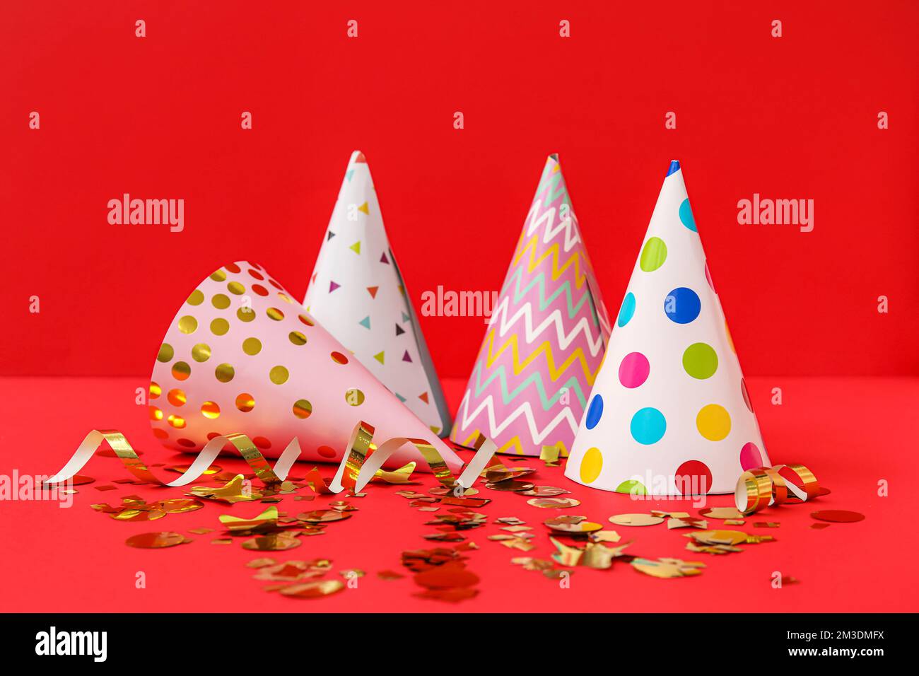 Party hats and confetti on red background Stock Photo - Alamy