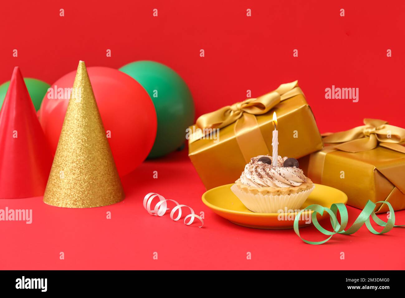 Birthday cake, party hats, gifts, balloons and confetti on red ...