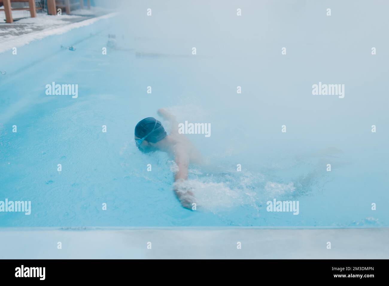 Fit swimmer male training swim in open winter swimming pool with fog ...