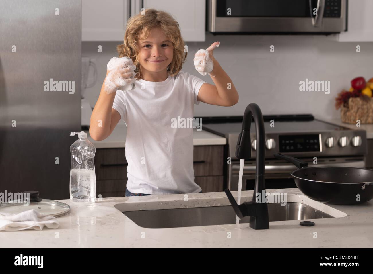 Child washing dishes with water and soap near sink in kitchen Stock ...