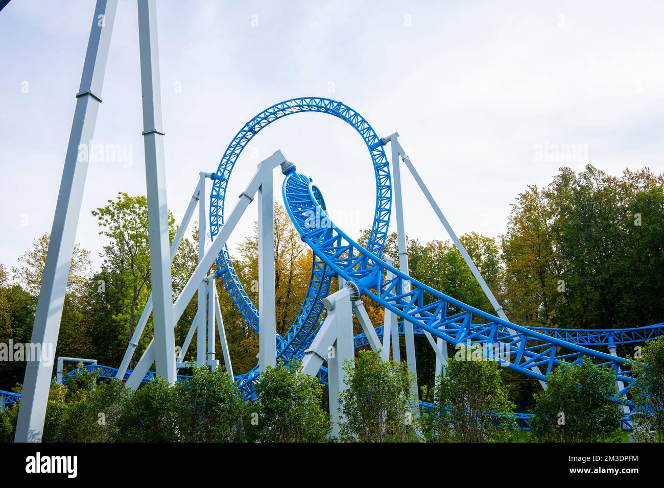 Part of a blue rollercoaster in amusement park and green trees over ...