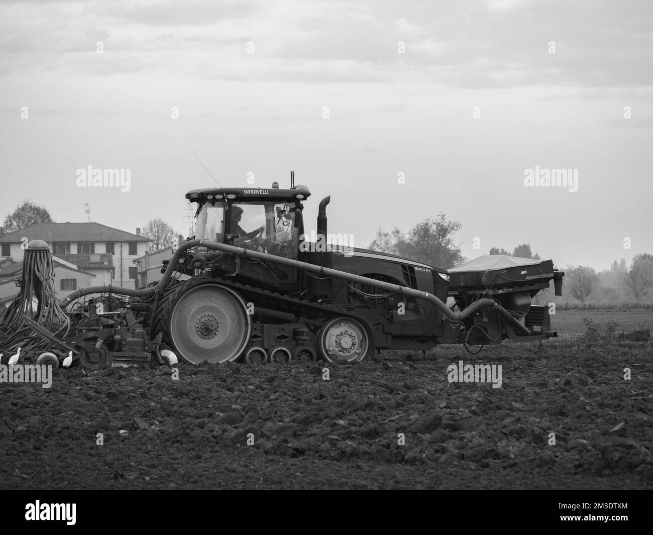 crawled tractor smoothing and seeding land in autumn in black and white ...