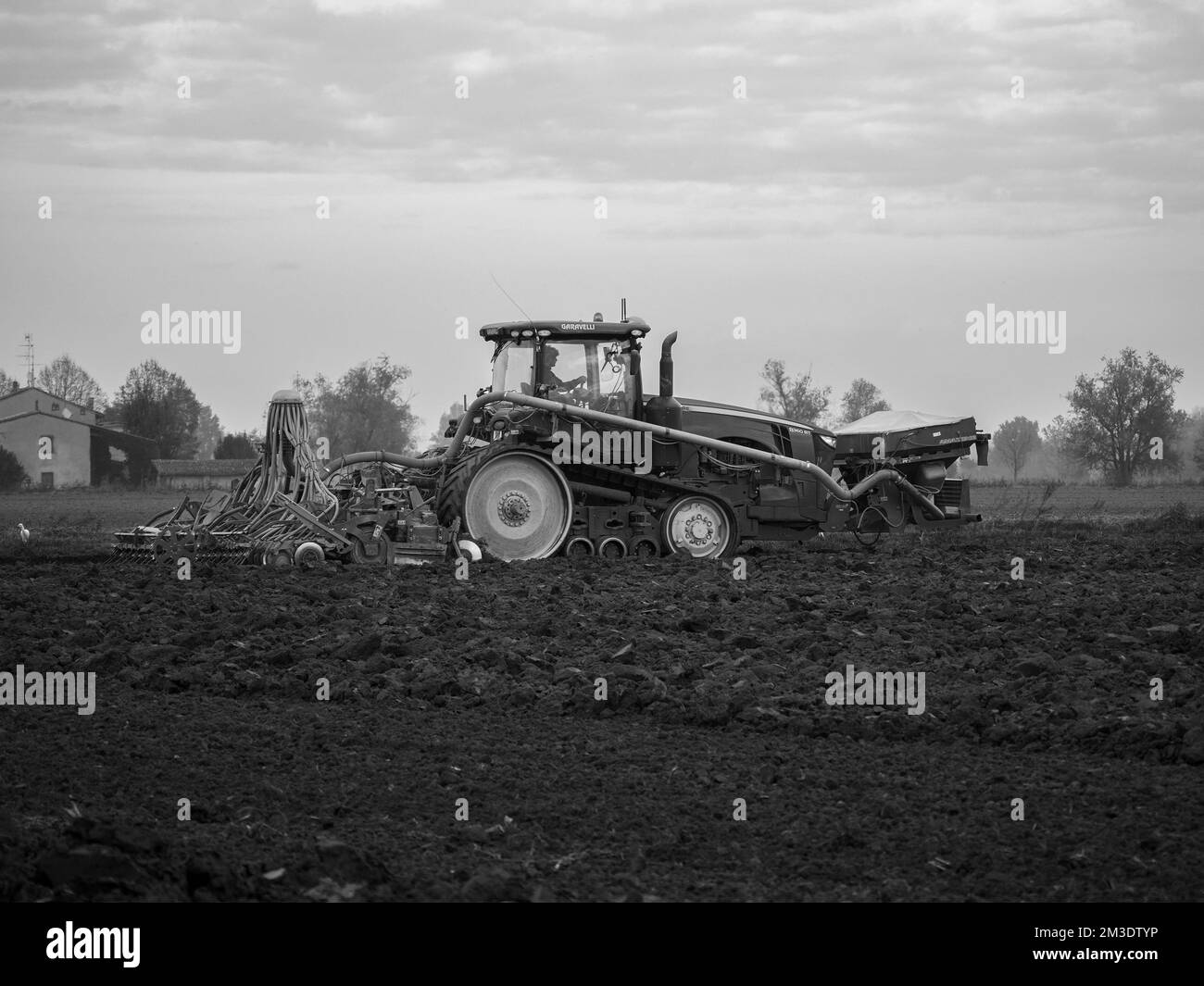 crawled tractor smoothing and seeding land in autumn in black and white ...