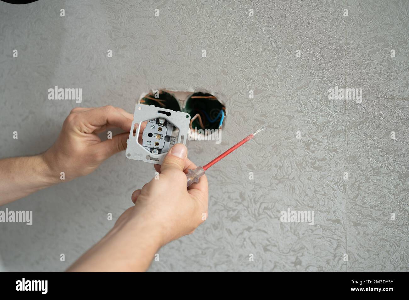 electrician connects the sockets to the electrical wires on the wall ...