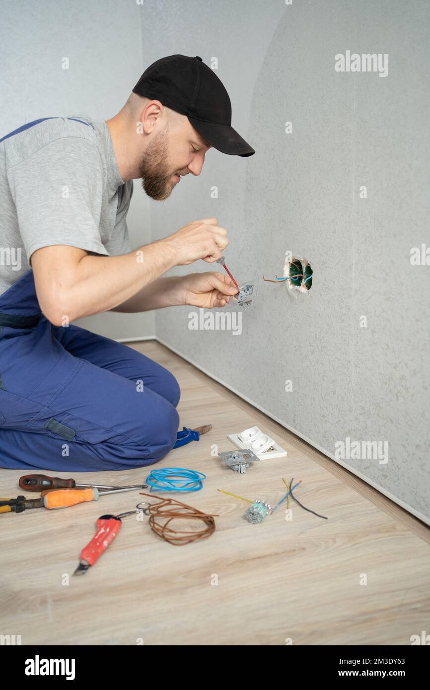 Electrician installing wall socket on the white wall indoors ...