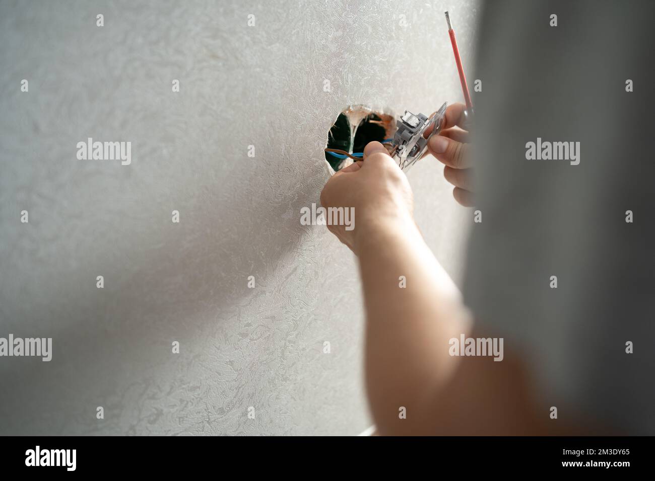 Close-up of electrician hands with screwdriver installing wall socket ...