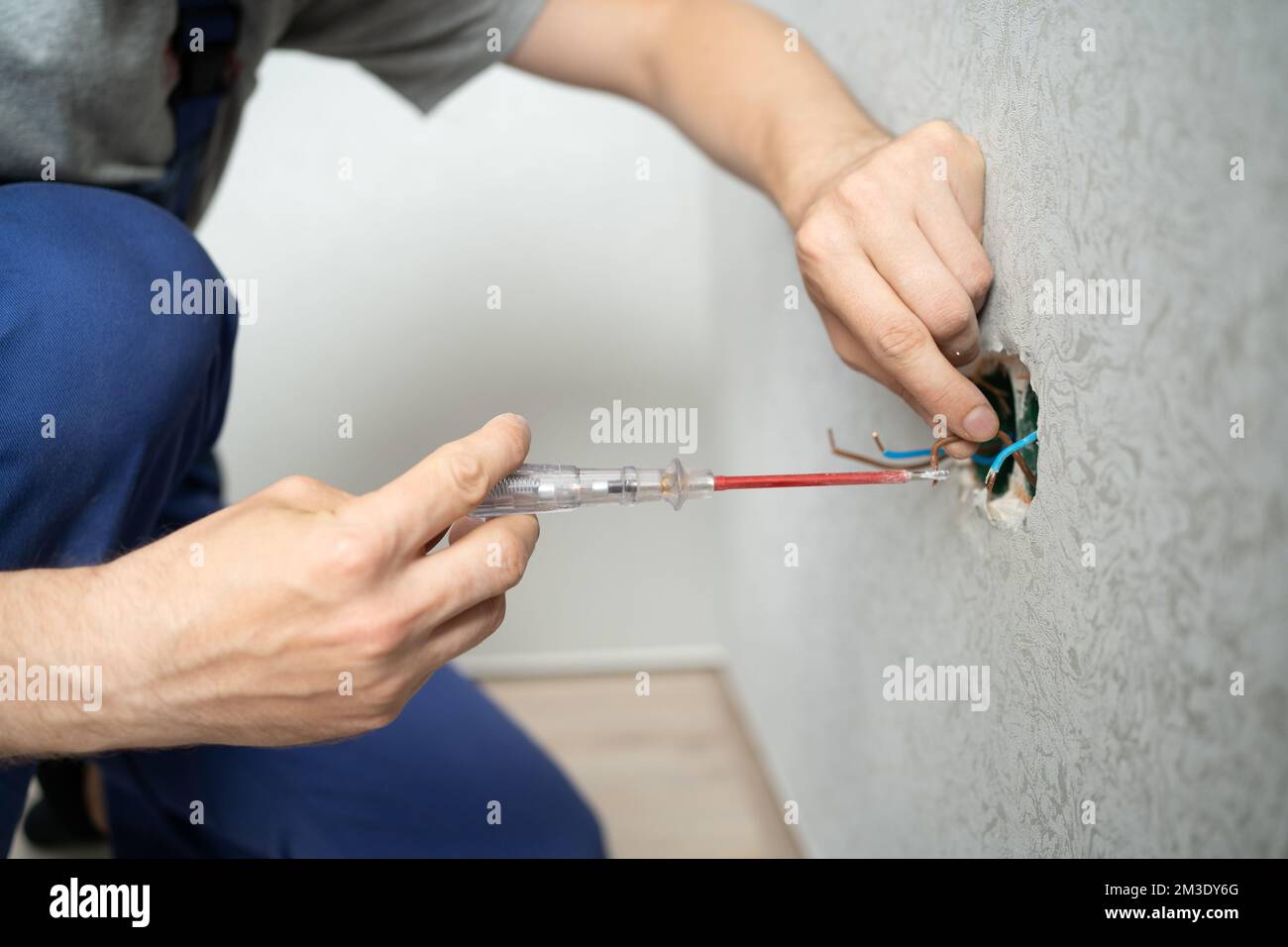 electrician connects to the electrical wires on the wall using ...