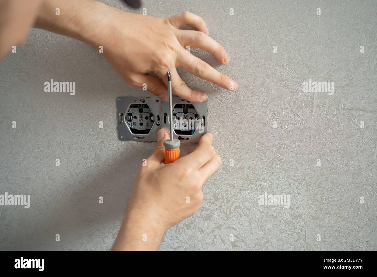 electrician connects the sockets to the electrical wires on the wall ...