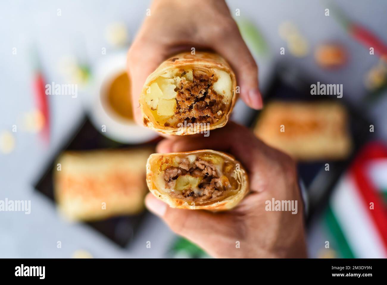 Hands holding Mexican burritos with chorizo, potato, cheese and beef ...