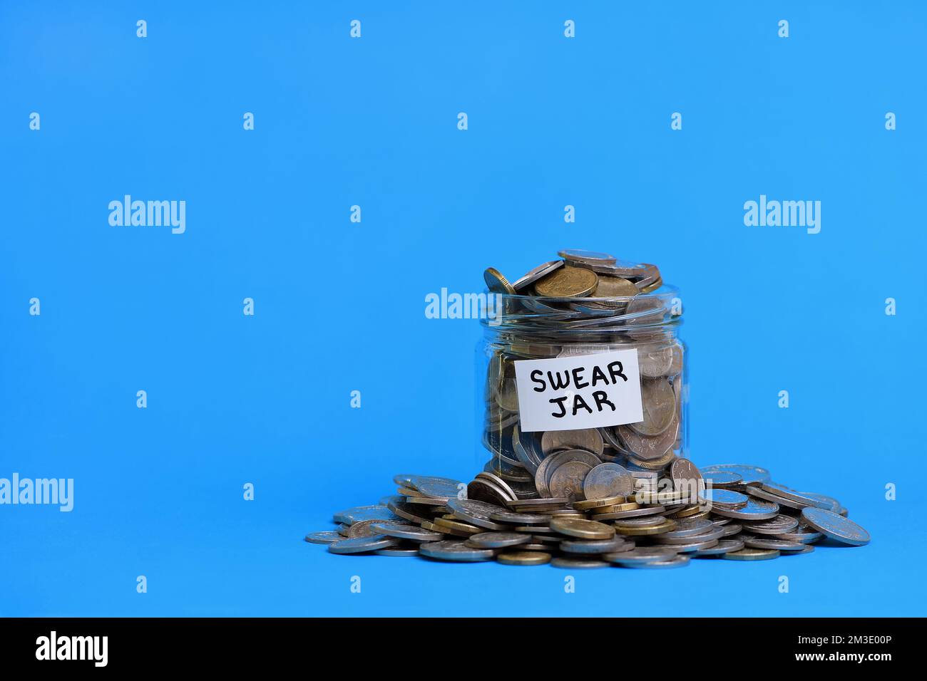 A glass Swear Jar overflowing with Australian coins to illustrate the ...