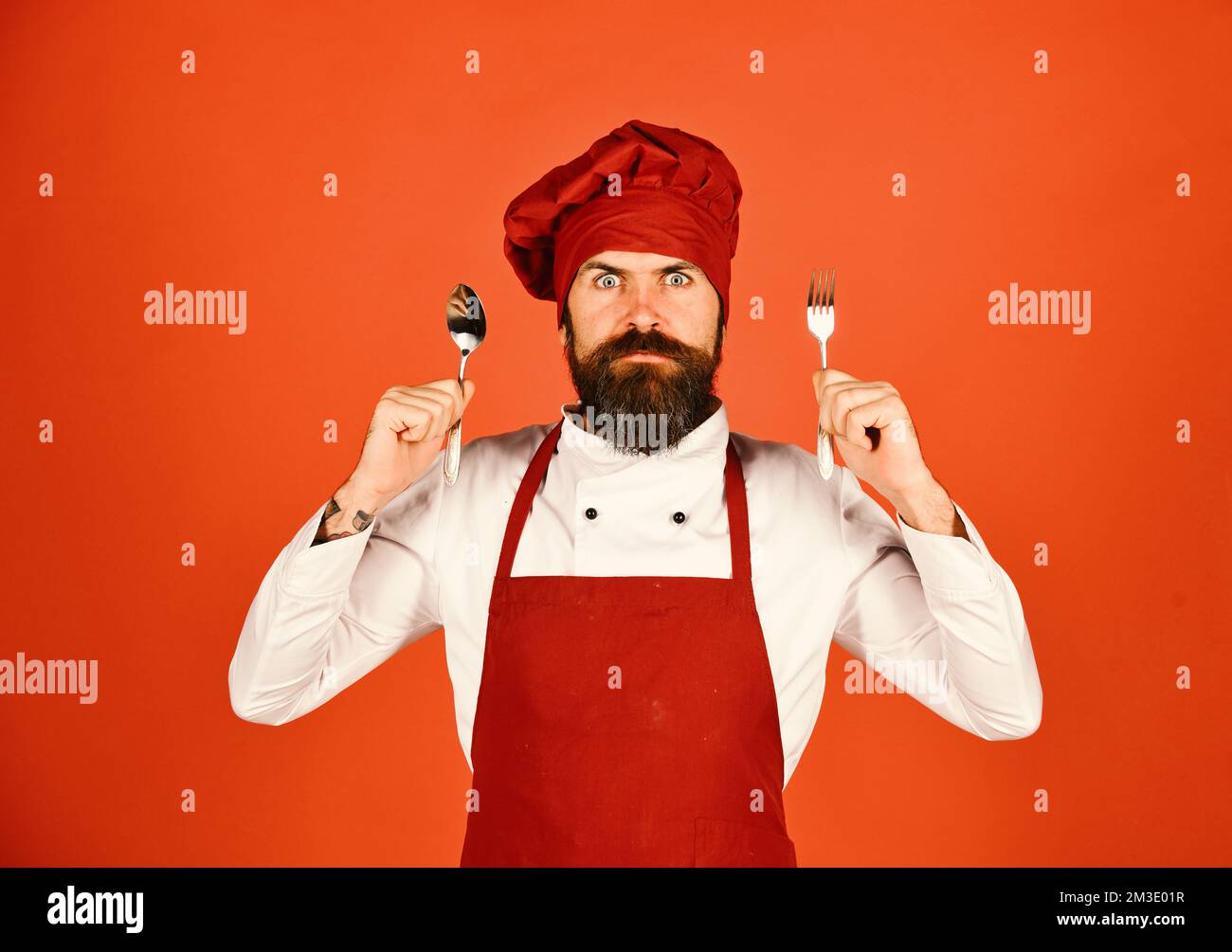 Cook with surprised face holds spoon and fork Stock Photo - Alamy