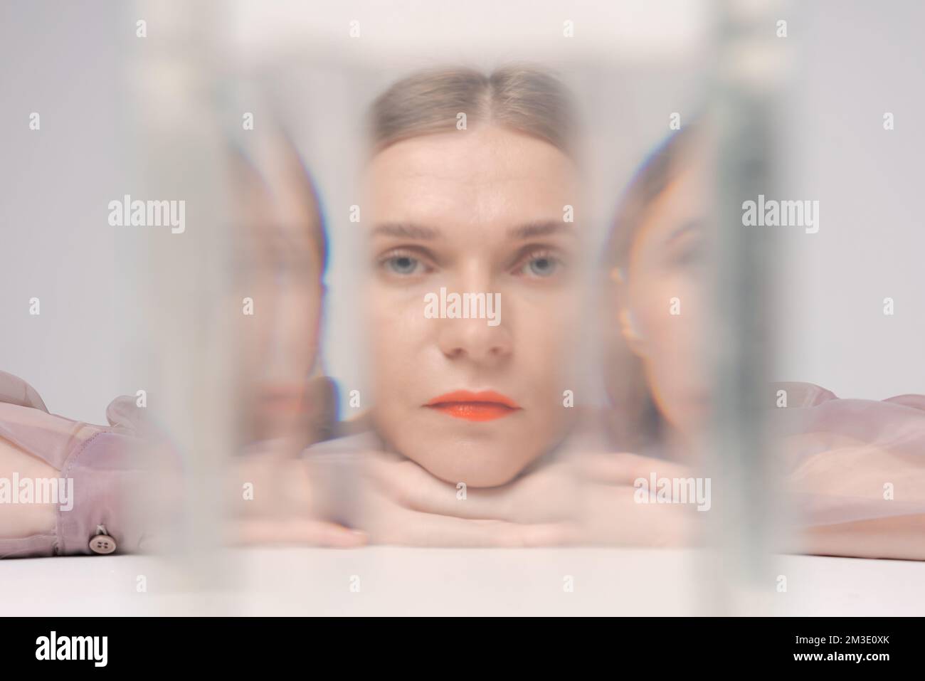 Beautiful woman looking through glass water looks into camera, bright ...
