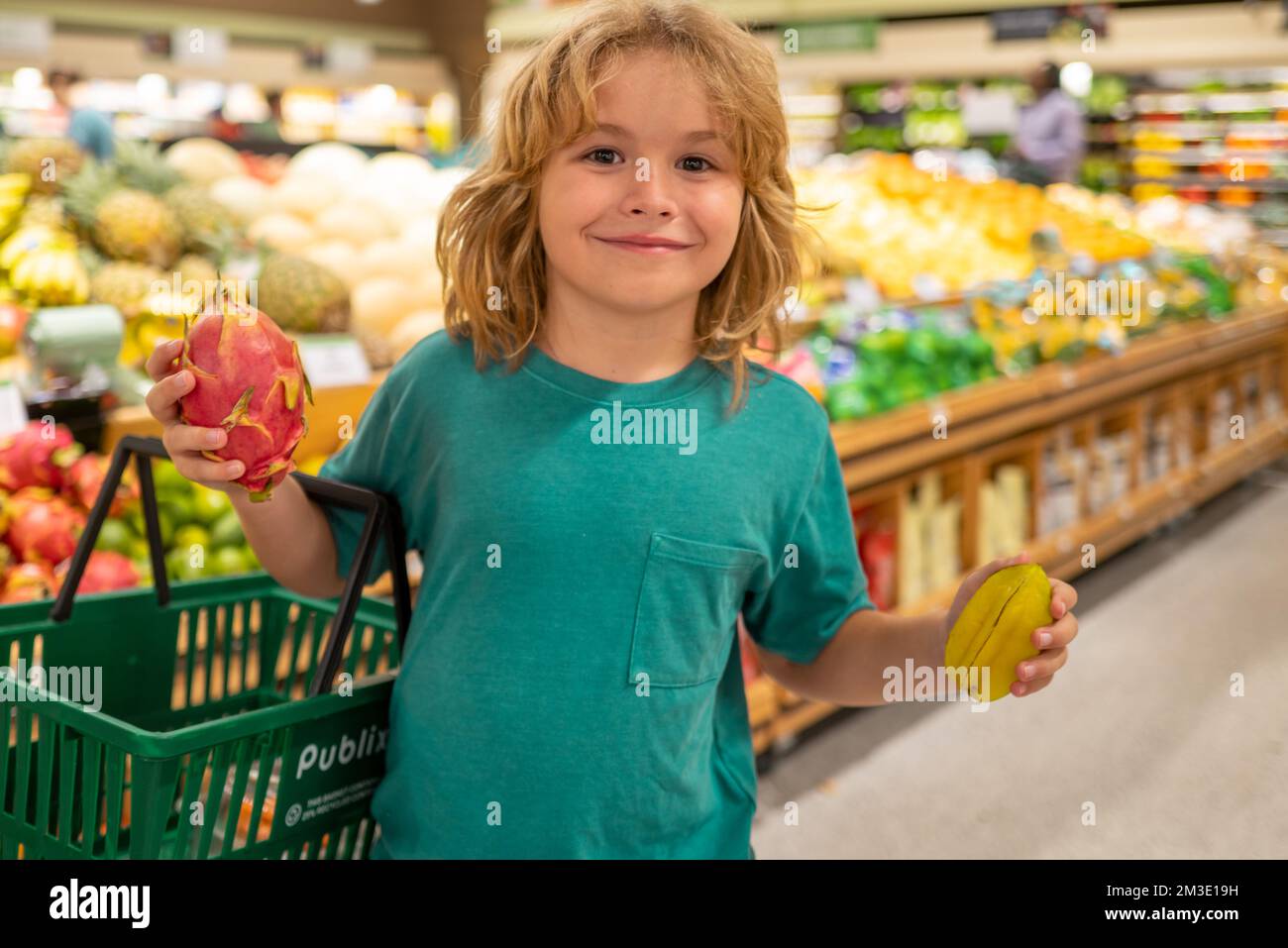 Kid with fruits. Kid choosing fruits and vegetables during shopping at ...