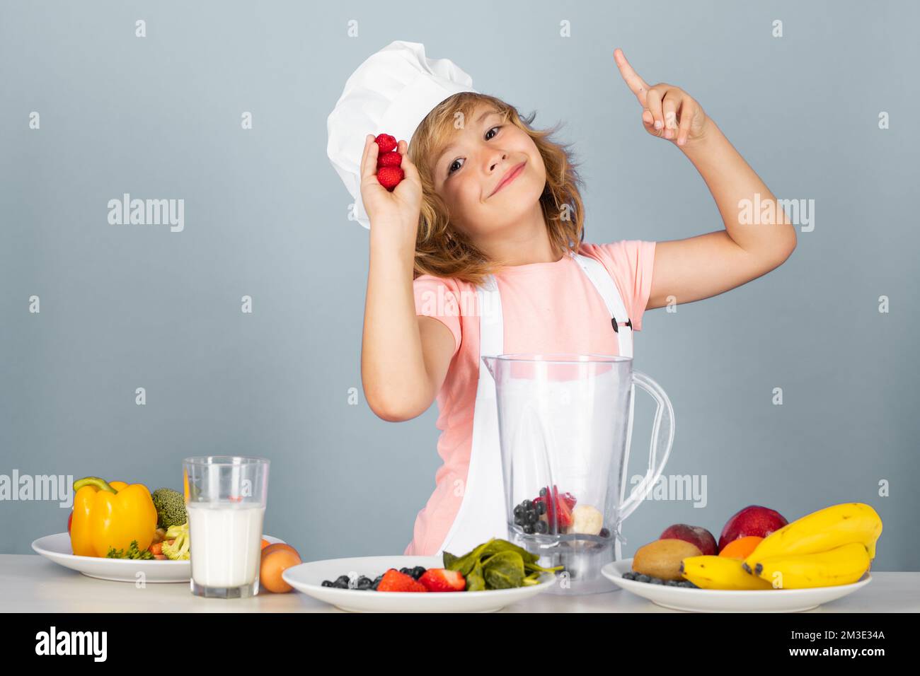 Cooking children. Chef kid boy making fresh raspberry smoothie for ...