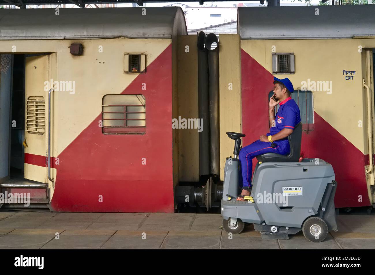 An cleaner sitting on a cleaning machine talking on his mobile; at ...