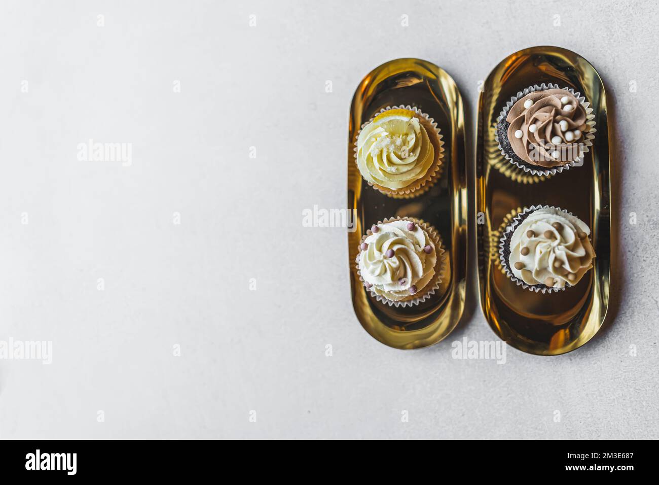 Top down view of four frosted cupcakes with sprinkles on small golden ...