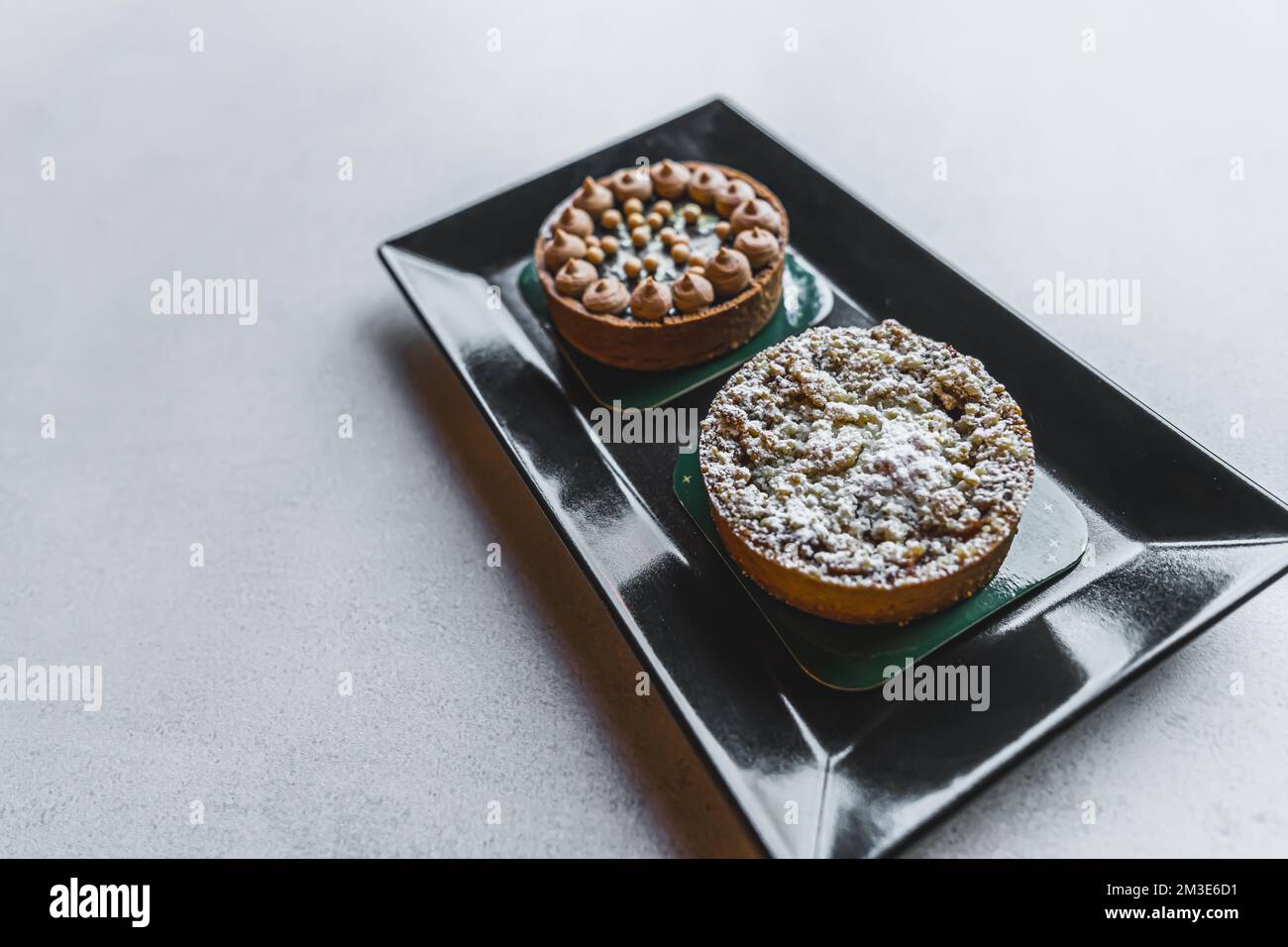 Fruit and chocolate small dessert tarts arranged on black platter on ...