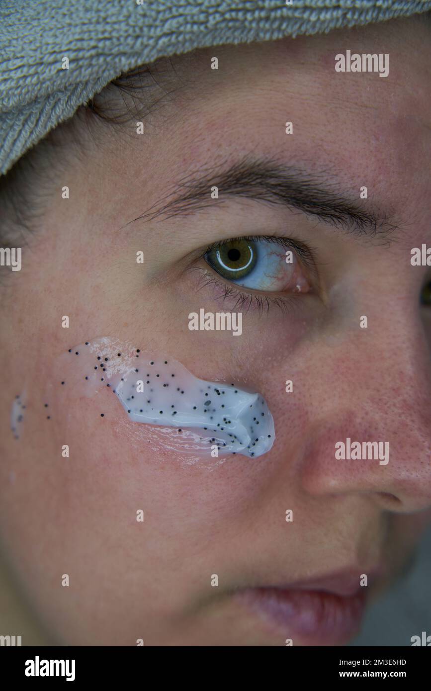 Woman with a towel over your head and smear of scrab on her face. Skin ...